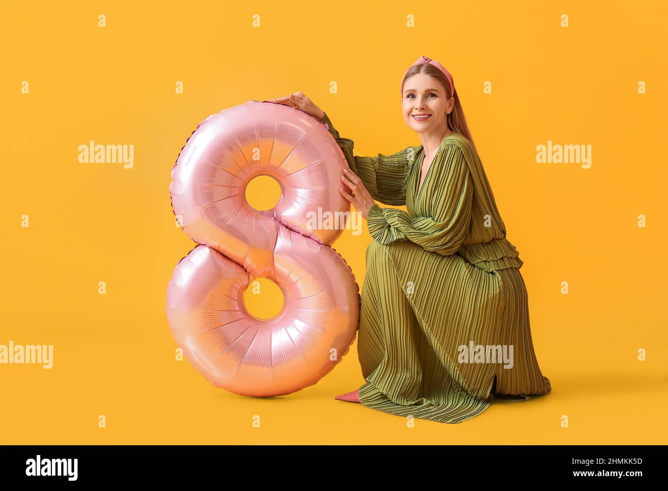 Beautiful woman with big balloon in shape of figure 8 on yellow ...