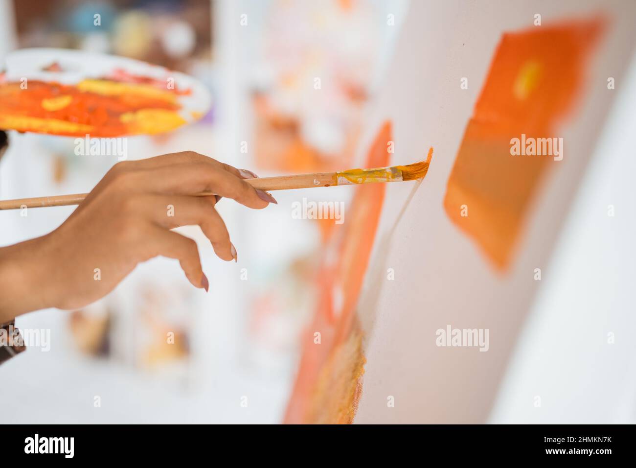 female artists hand holding a paint brush with color palette painting ...