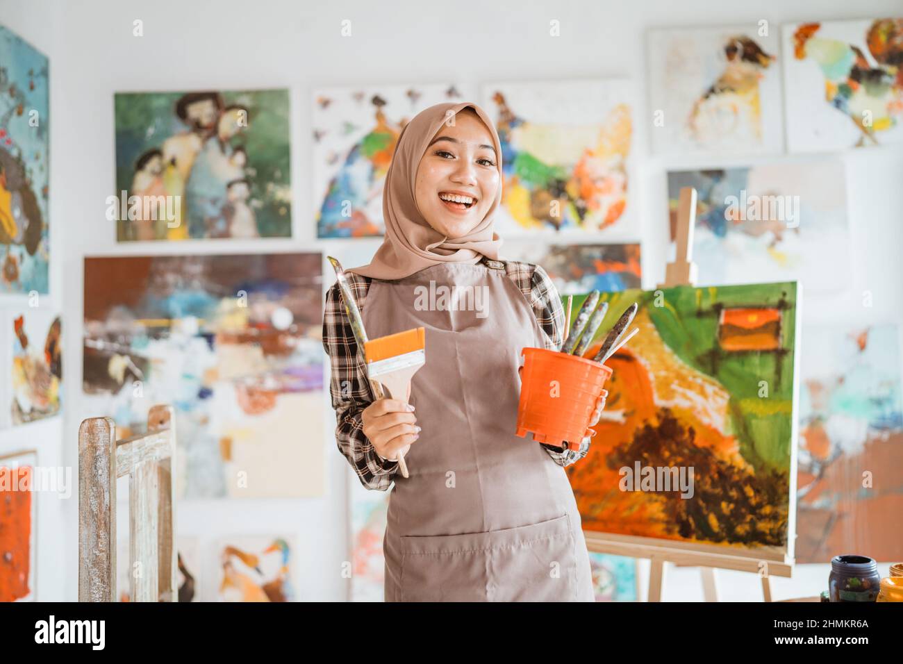 muslim female painter holding brush and bucket smiling Stock Photo - Alamy