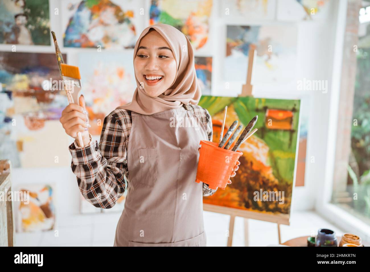 muslim female painter holding brush and bucket smiling Stock Photo - Alamy