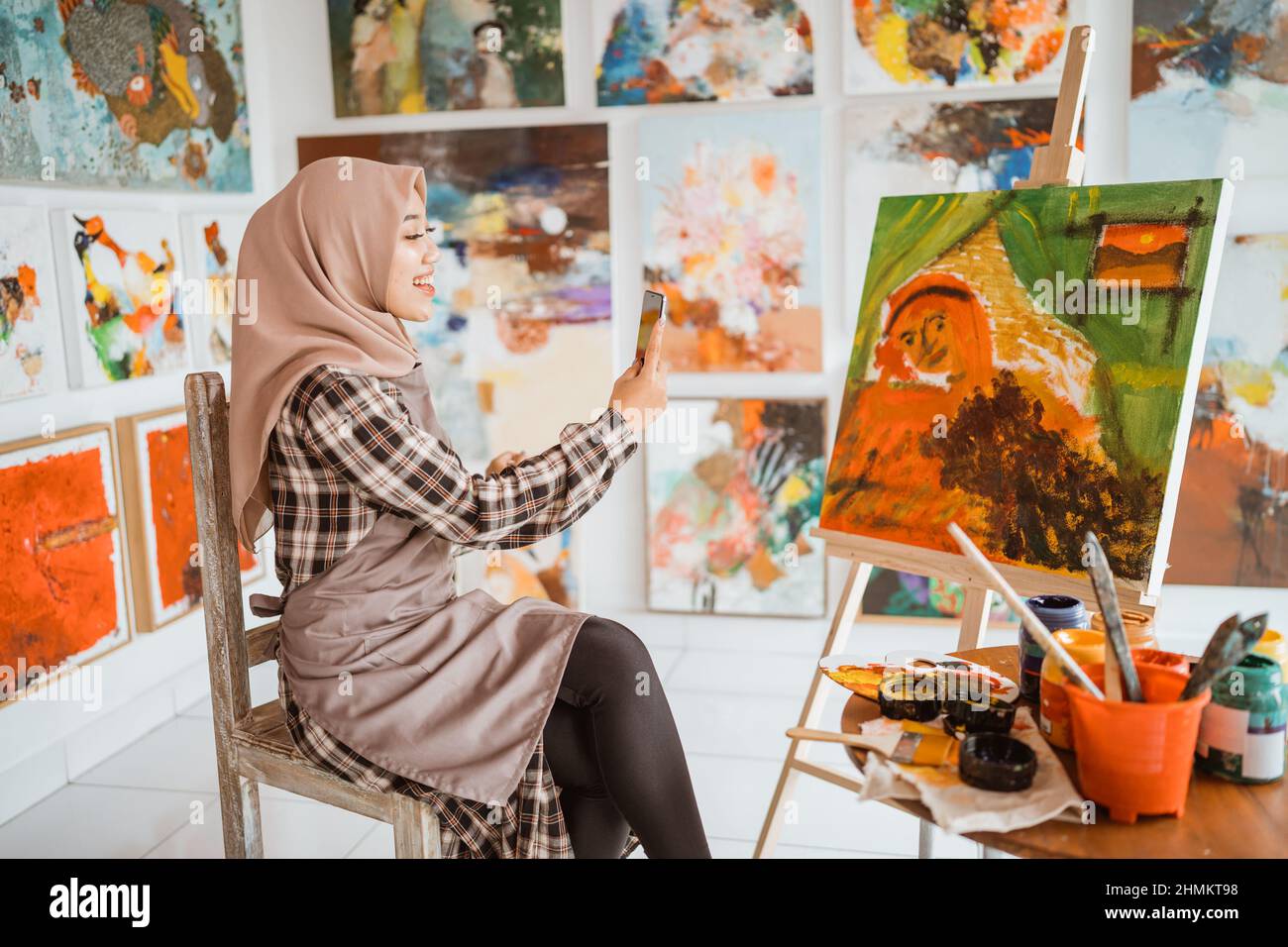 muslim female artist taking picture of her own painting using ...