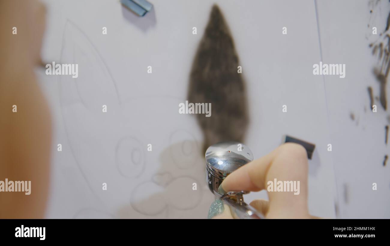 Woman artist learns to paint with airbrush with acrylic dye, paper and ...