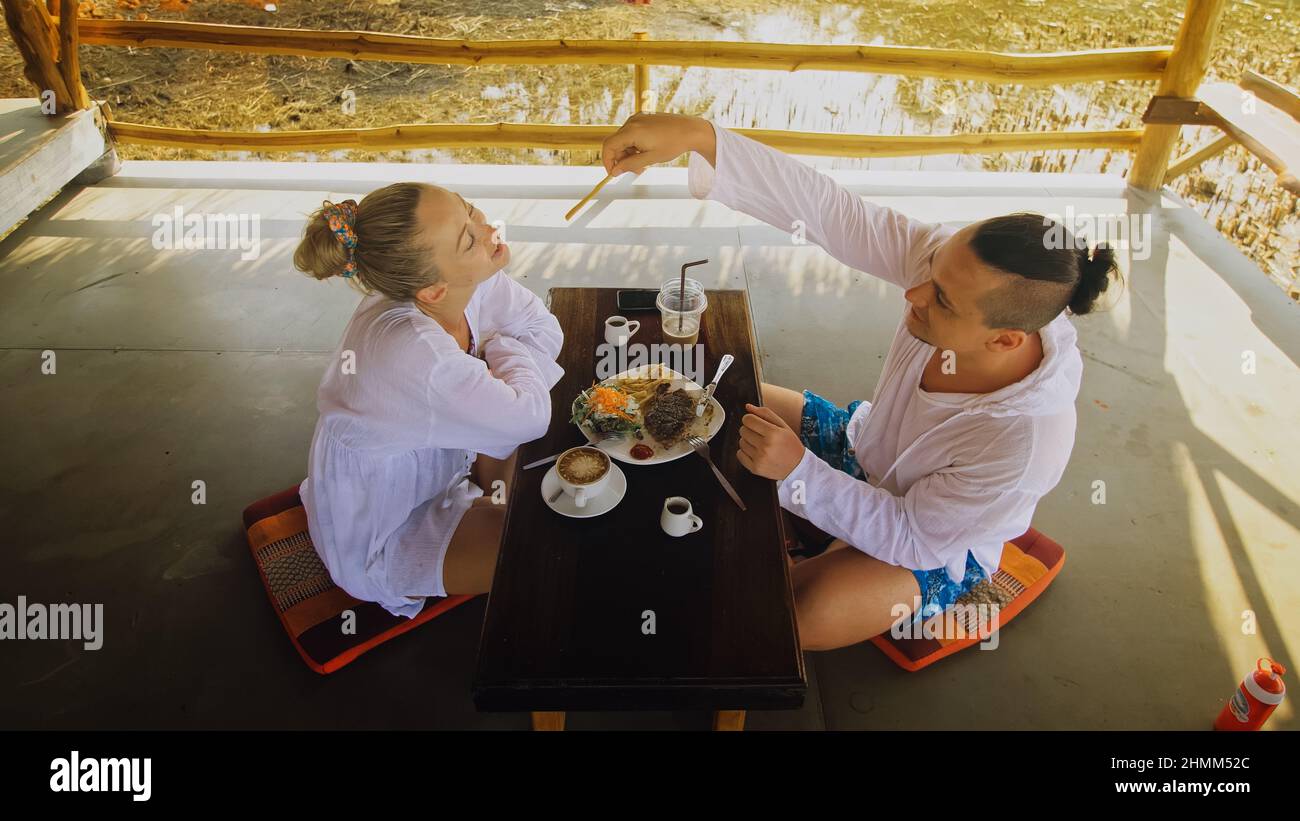 Attractive young man and woman eat and drink tasty beverages spending ...