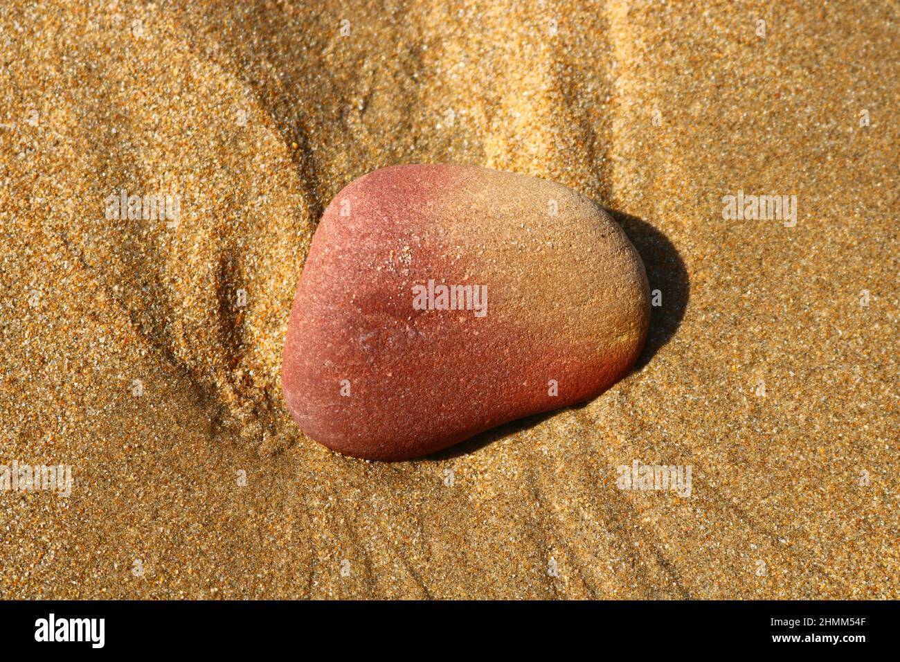 Red rock on beach sand Stock Photo - Alamy