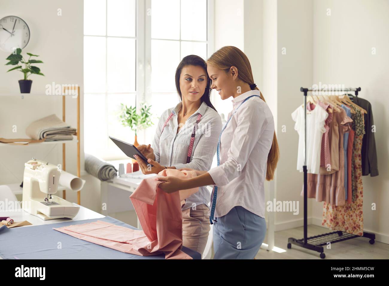 Two female tailors work on tablet creating new garment line Stock Photo ...