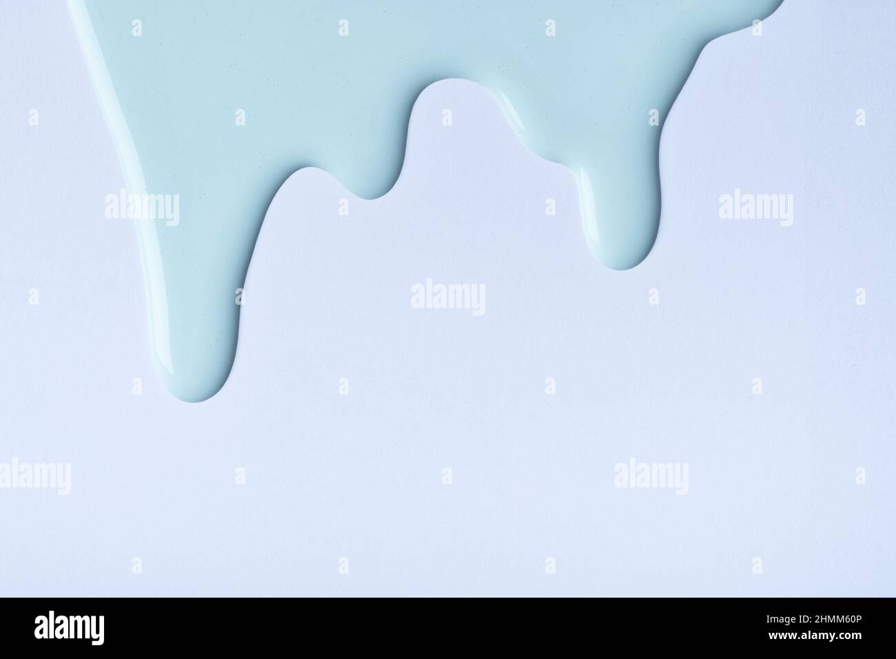 Light blue liquid drops of paint color flow down on sky background ...