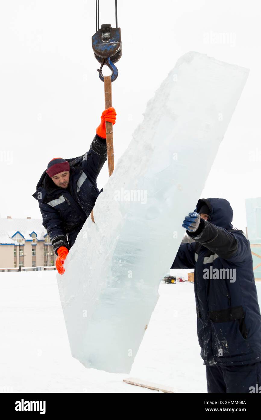 The installer stands on the ice block holding on to the tape sling ...