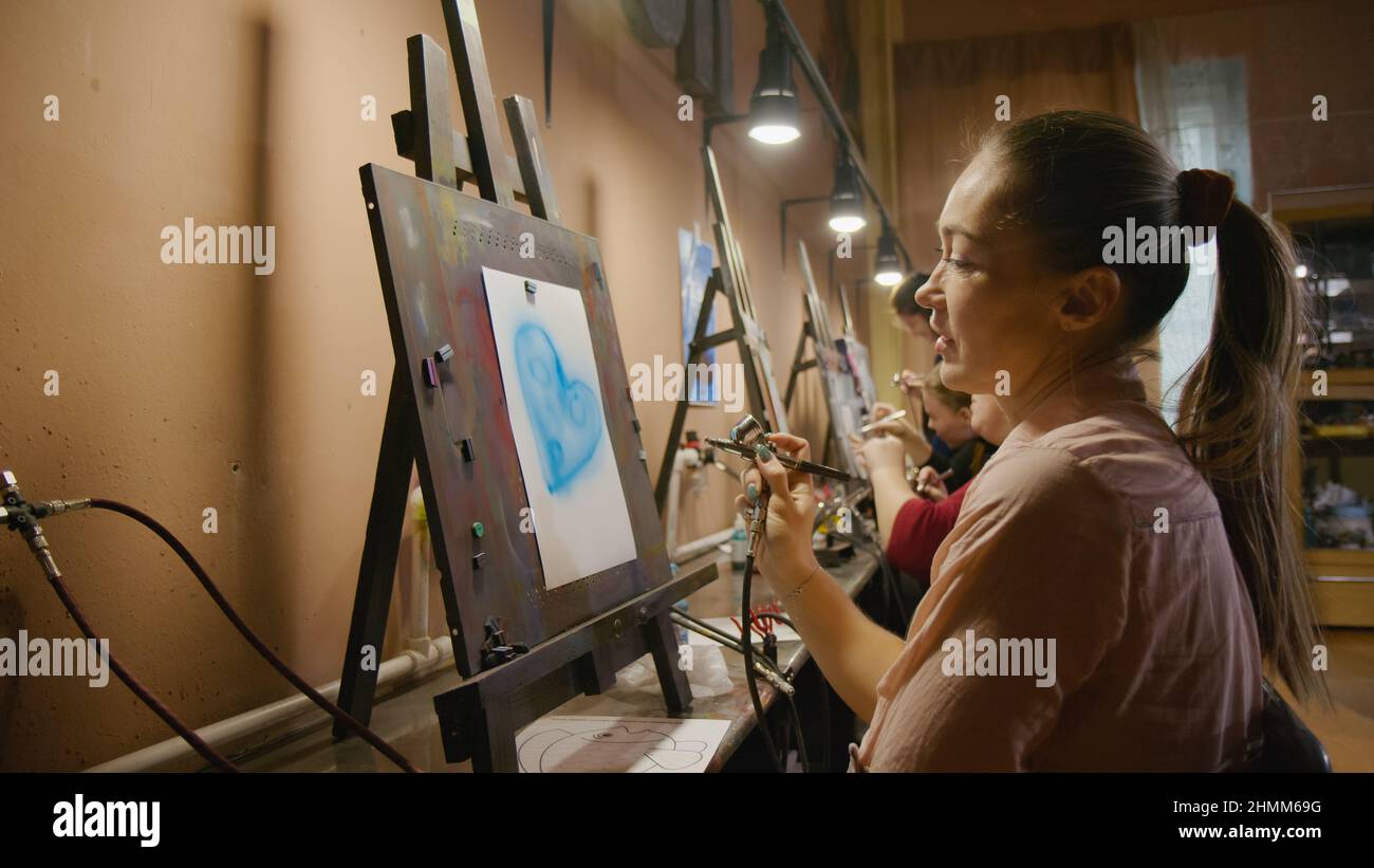 Woman artist learns to paint with airbrush with acrylic dye, paper and ...