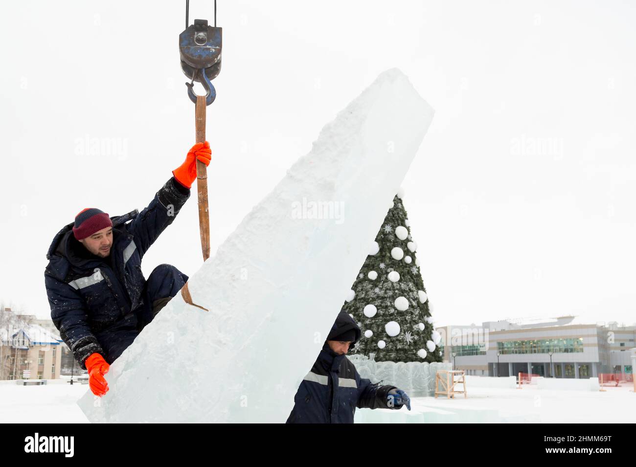 The installer stands on the ice block holding on to the tape sling ...