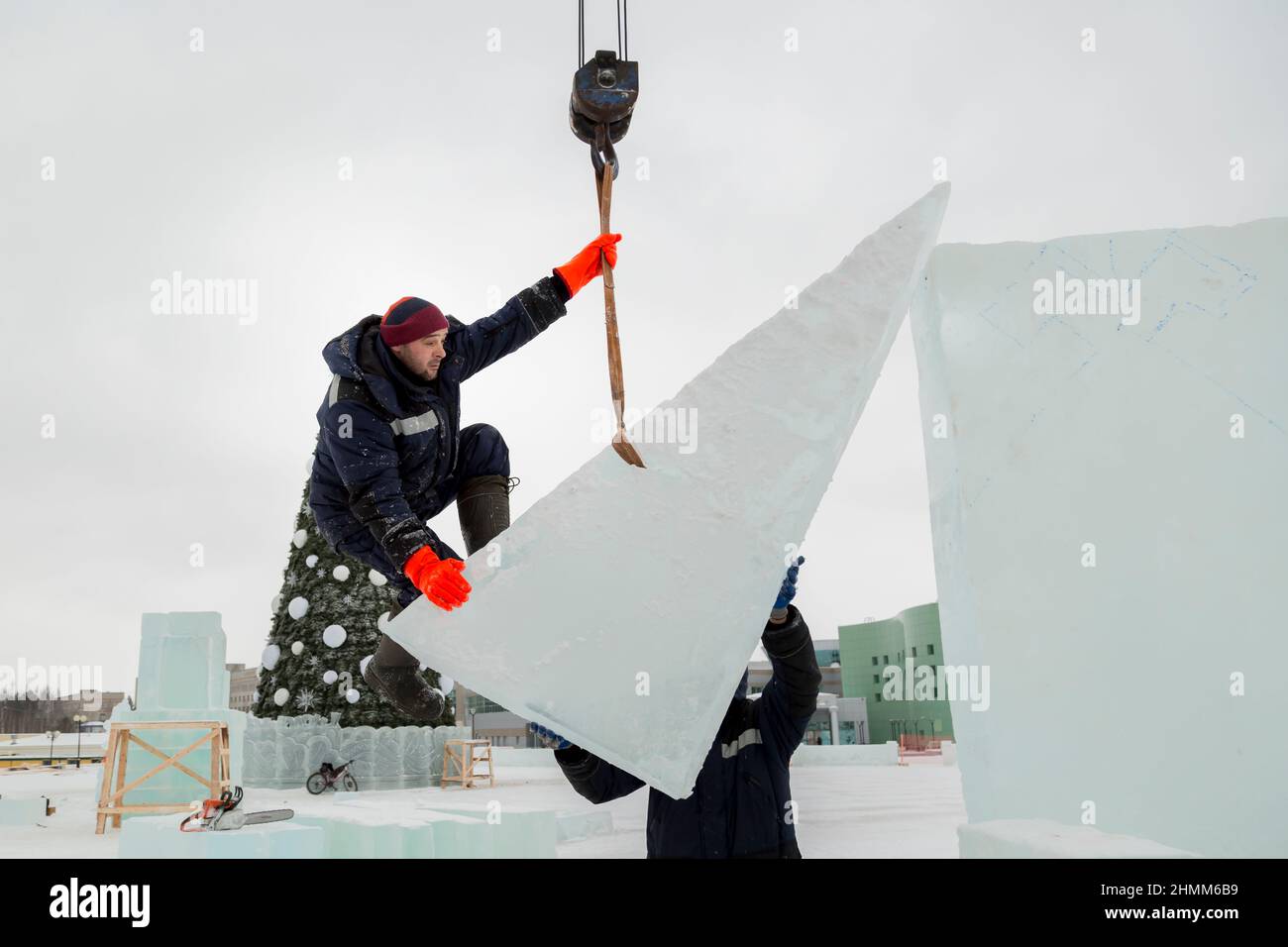 The installer stands on the ice block holding on to the tape sling ...