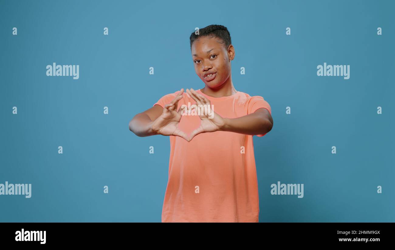 Young woman doing heart shape symbol with hands in studio. Affectionate ...