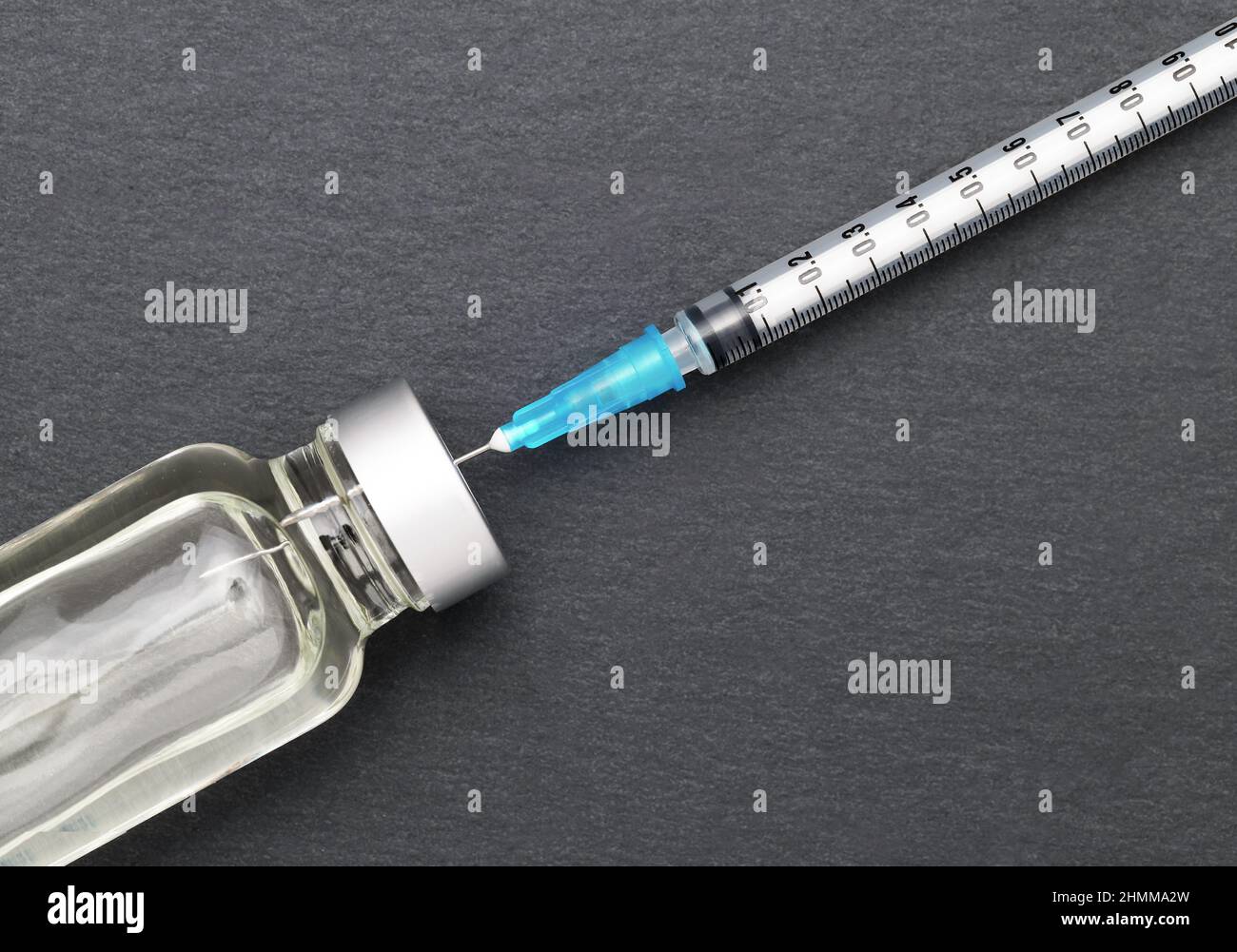 Liquid medicine in vials and injection syringe on dark gray background ...