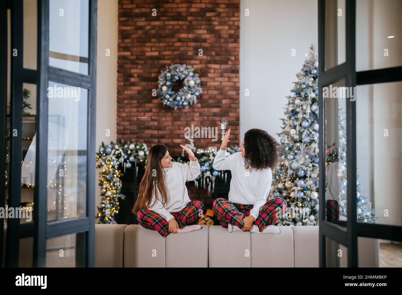 Two female student friends sitting on the couch at home. High five Stock Photo - Alamy
