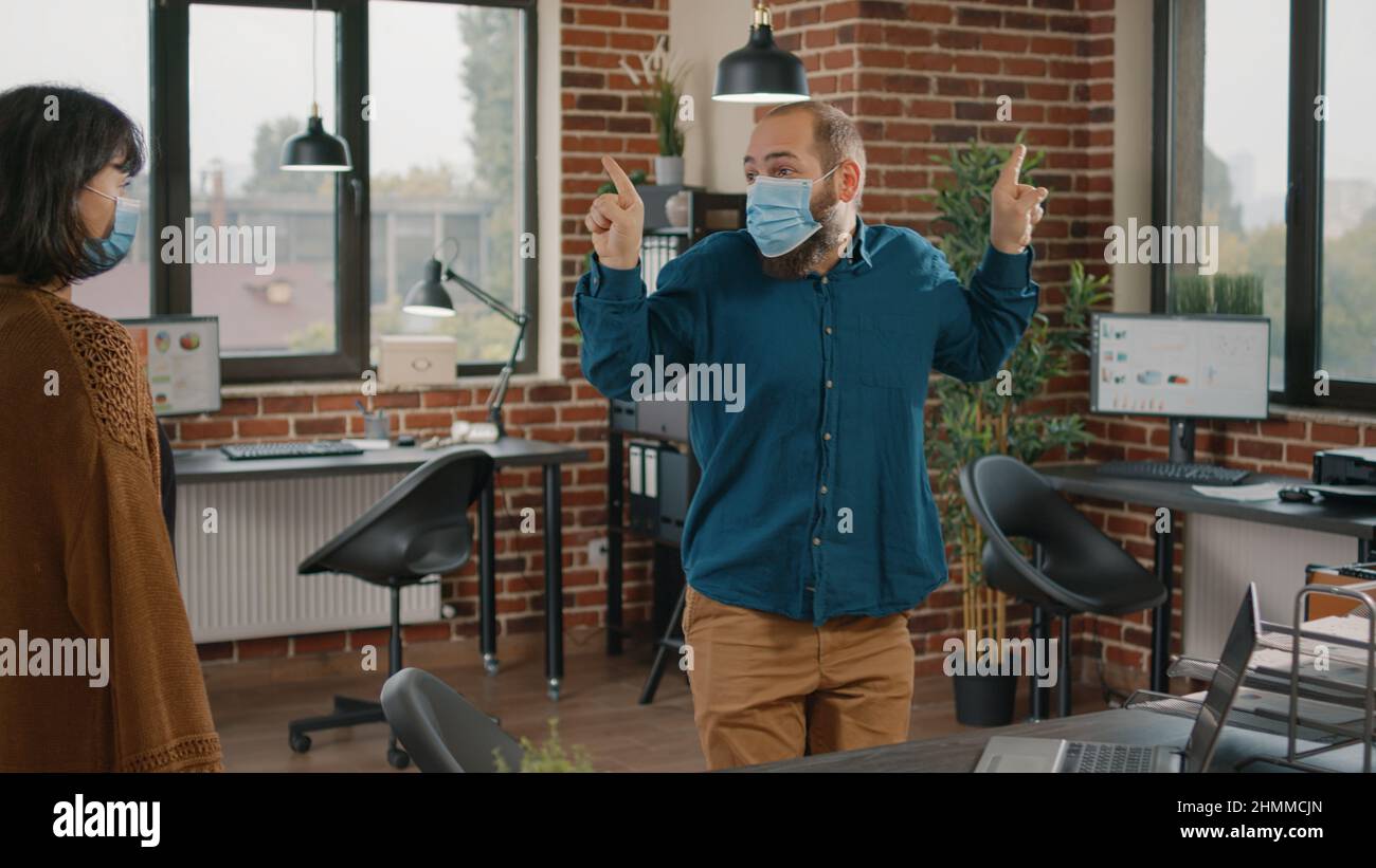 Happy employee dancing after winning successful deal, wearing face mask ...