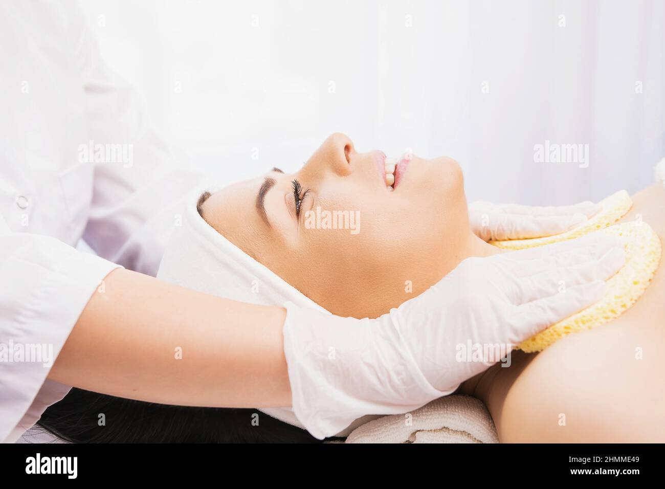 Professional female cosmetologist using sponges to cleansing the neck ...