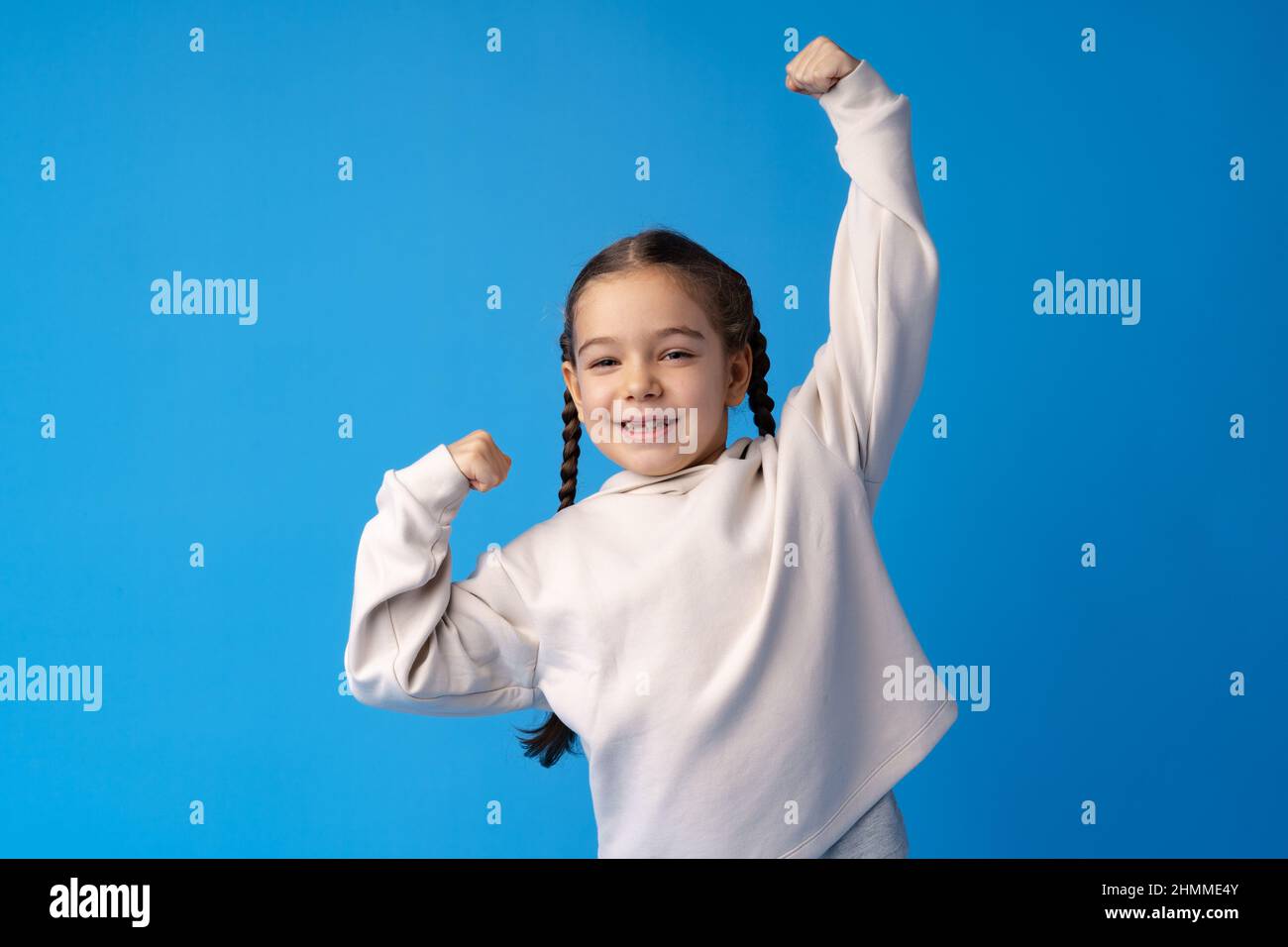 Little cute girl showing her strength on blue background Stock Photo ...