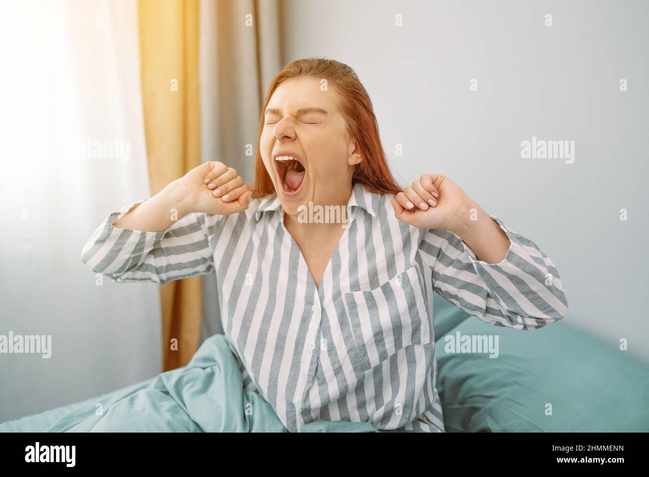 Beautiful young tired caucasian woman stretches waking up background ...