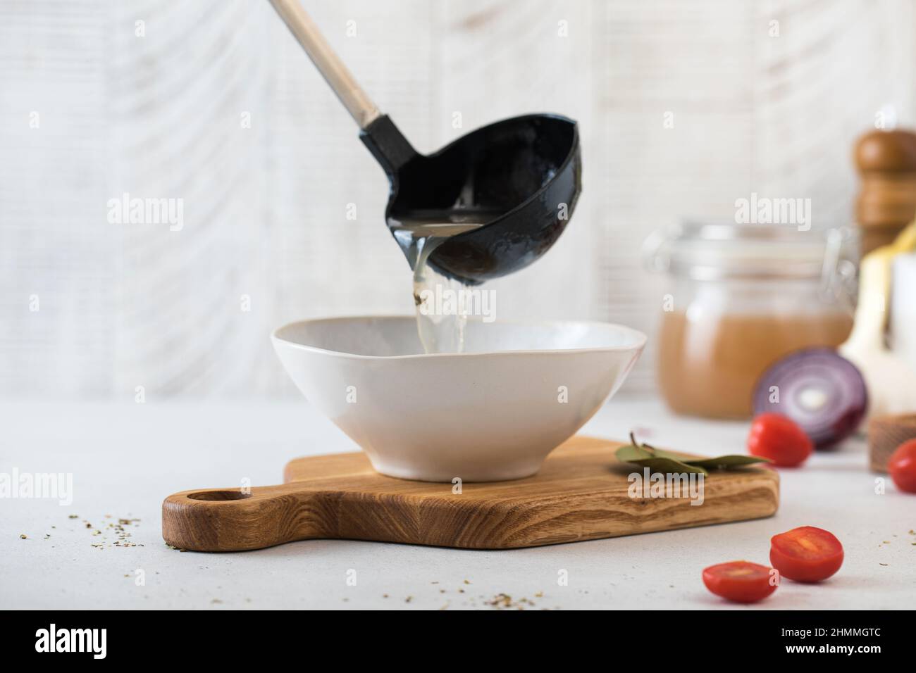 A ladle is poured with a healthy homemade bone broth into a plate Stock ...