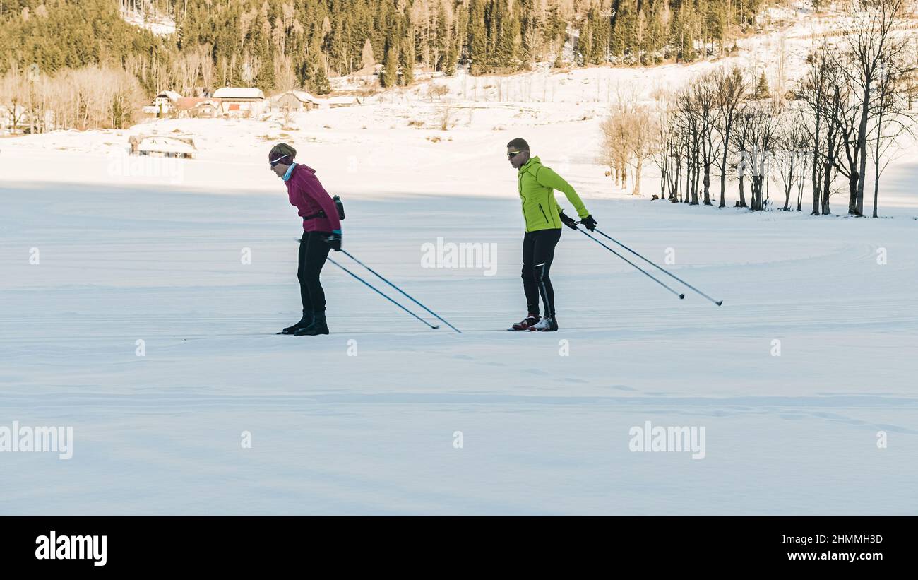 Caucasian woman and man skiing, moving by striding forward in classic ...