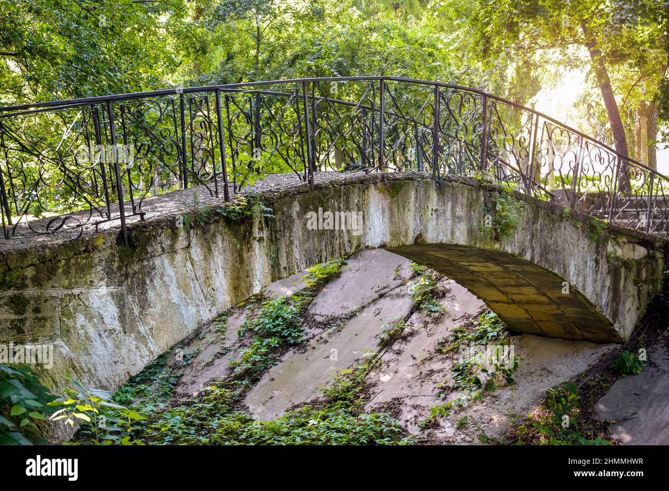 Old concrete arched footbridge with wrought iron railings against ...