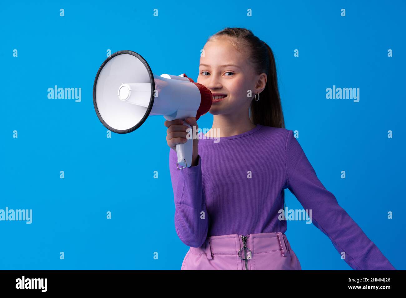 Child girl using megaphone against blue background Stock Photo - Alamy