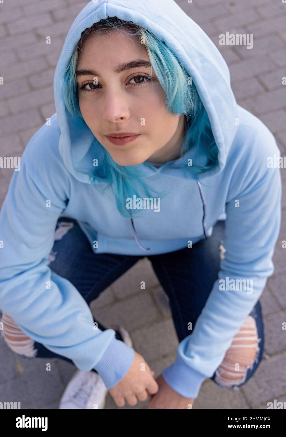 Blue haired Teenage girl in light blue oversize hoodie and looking into ...
