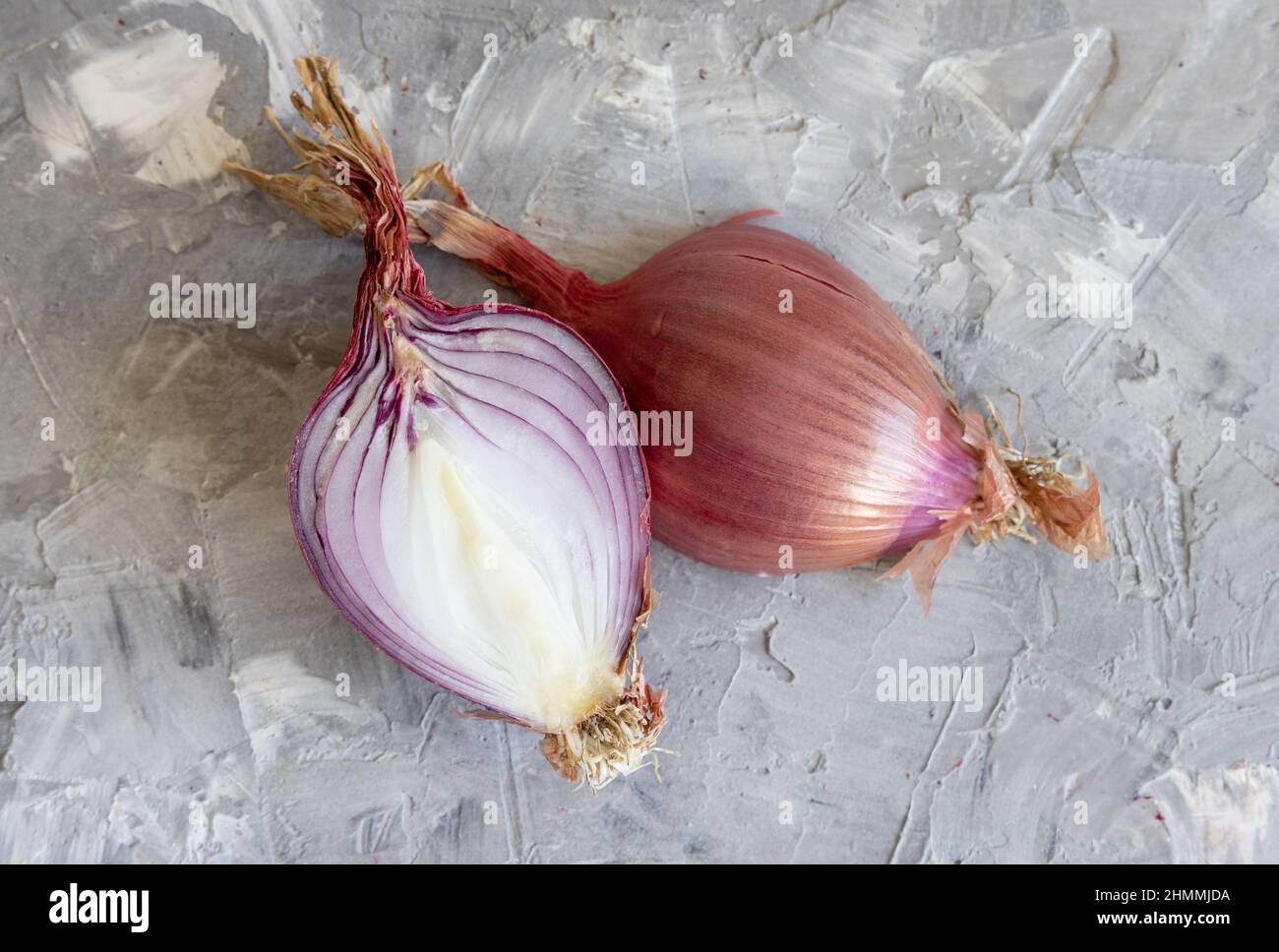 Half of Red tropea onions on a grey table close up. Traditional local ...