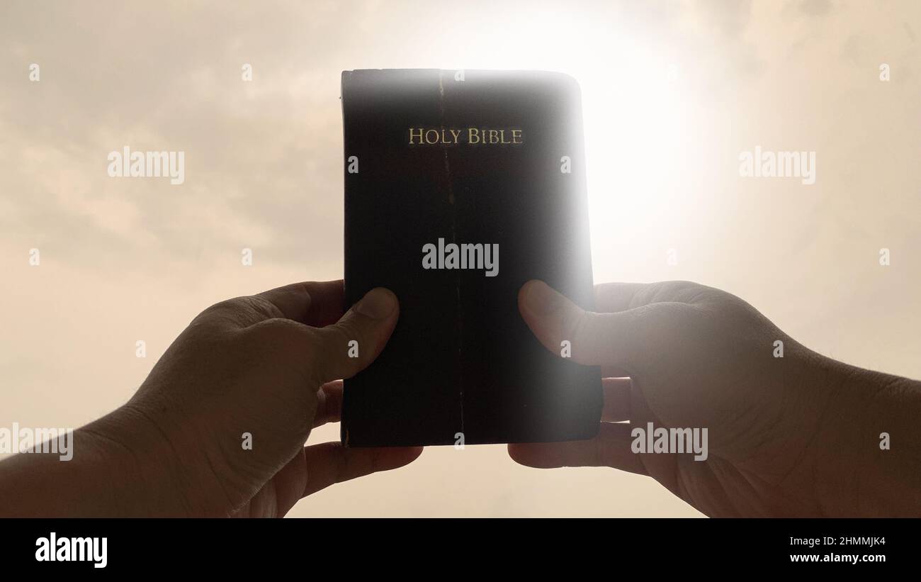 Hand holding an old Holy Bible with shining light background. Christian ...