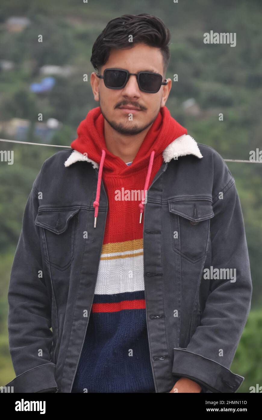 Portrait of a good looking young guy wearing sunglasses, looking at ...