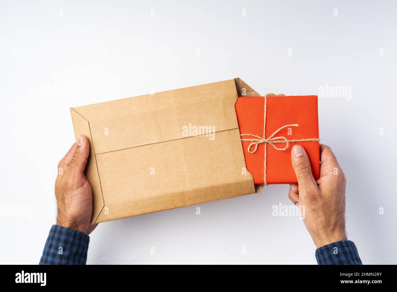 Close up of hands taking gift box out of delivery parcel above white ...