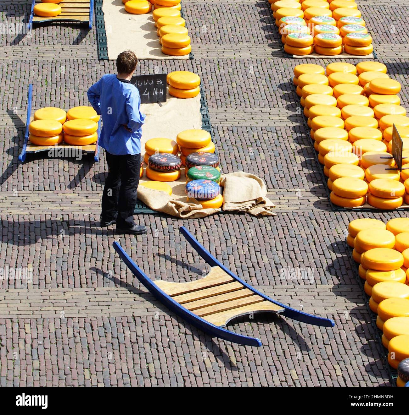Group of cheese carriers standing by stacked Gouda cheese on a square ...