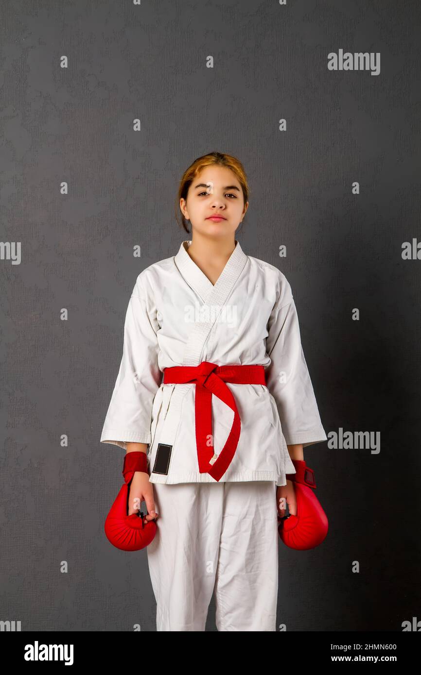A young karateka girl in a white kimono and red competition outfit ...
