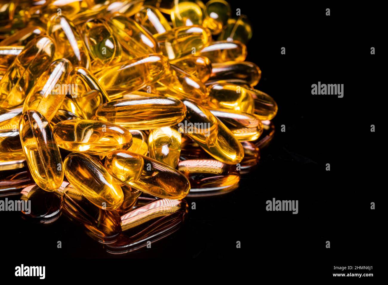 Macro Close up of Omega 3 gel capsule on a reflective black background ...