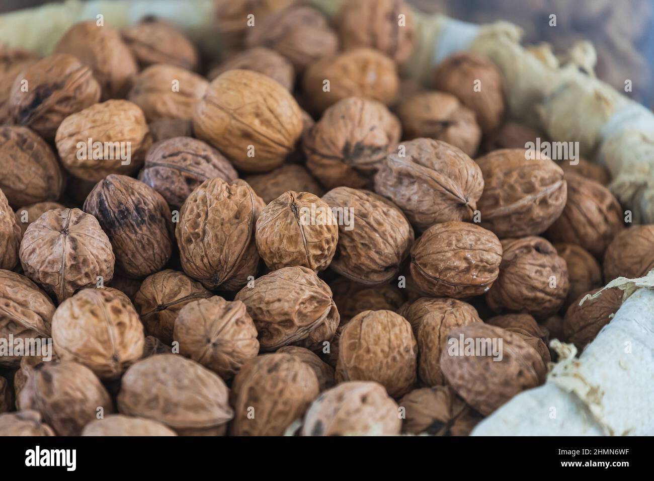 A pile of unpeeled walnuts. Raw fresh walnut with shell on a display ...