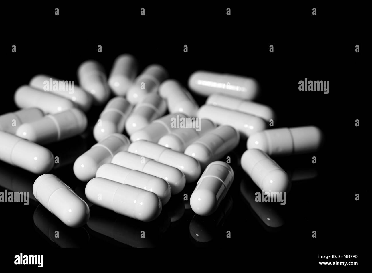 Macro Close up of white painkiller capsule on a reflective black ...