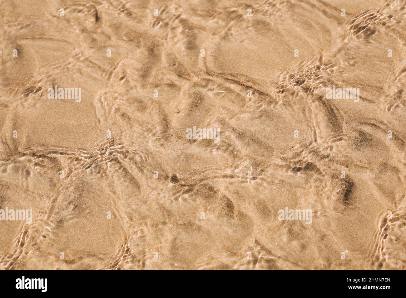 Sea waves and sun glare over the sandy coast. Sand texture background ...
