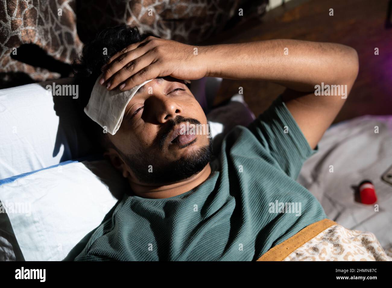 young indian sick man suffering from mild fever while sleeping at night ...