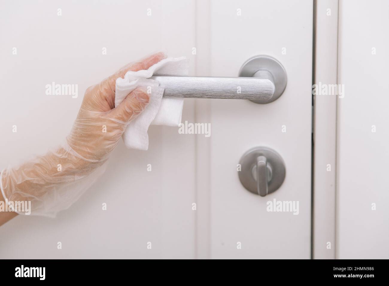 Cleaning door handles with wet wipe and white gloves. Woman hand using ...