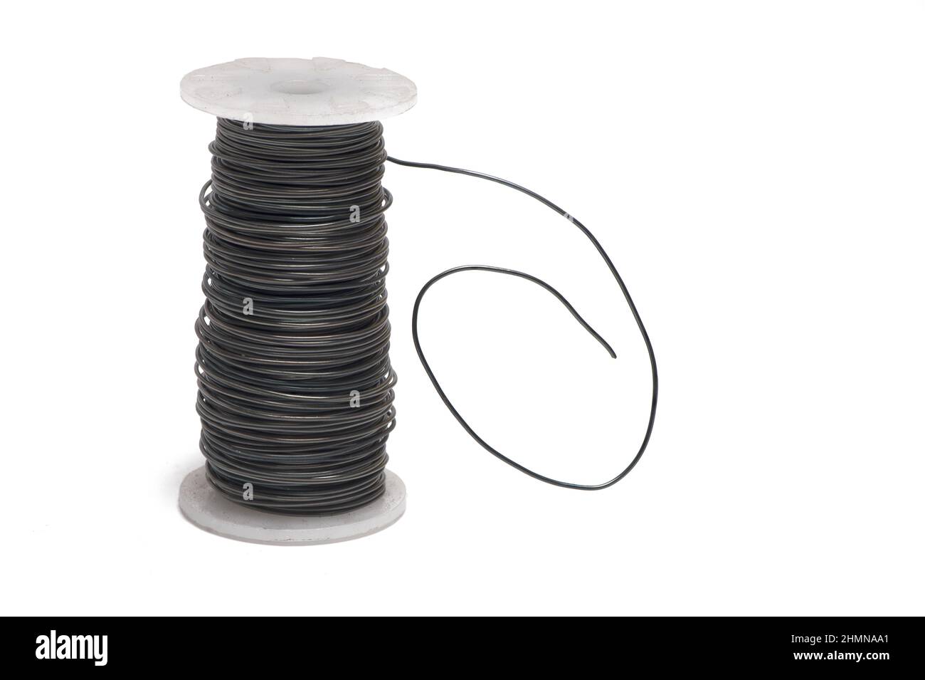Close up of a white plastic roll with dark metal wire wound on it and a ...