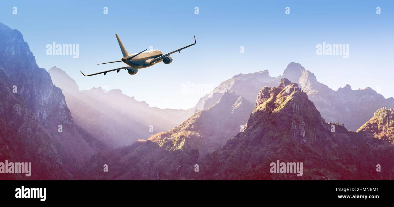 Airplane is flying over mountains in fog at sunset in summer. Landscape ...
