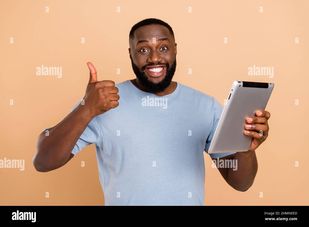 Portrait of attractive cheerful guy using device gadget showing thumbup ...