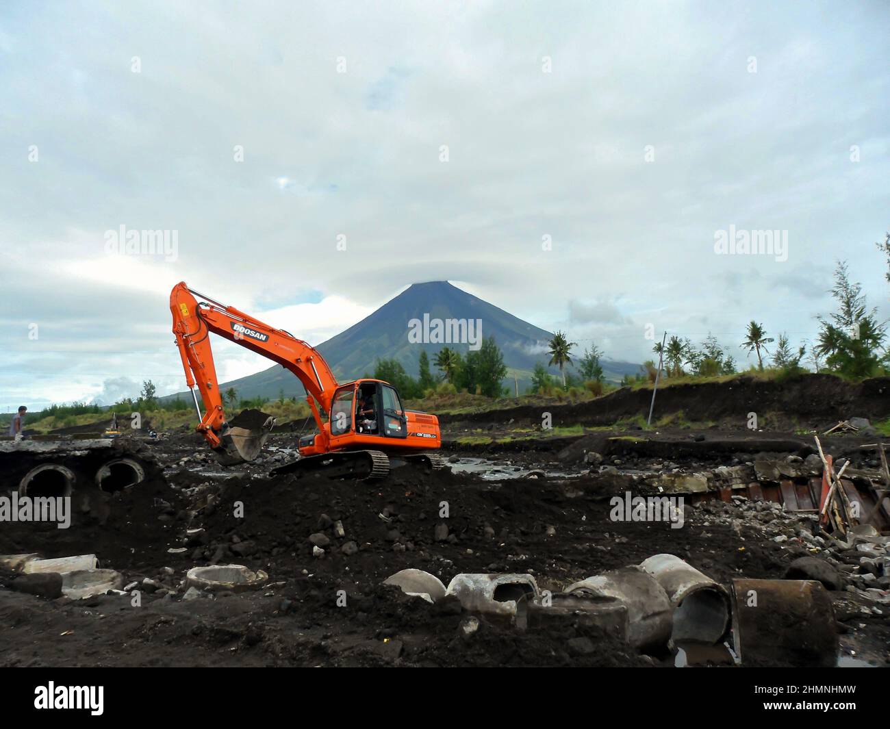 Excavator is digging in front of the majestic volcano Mayon in Cagsawa ...