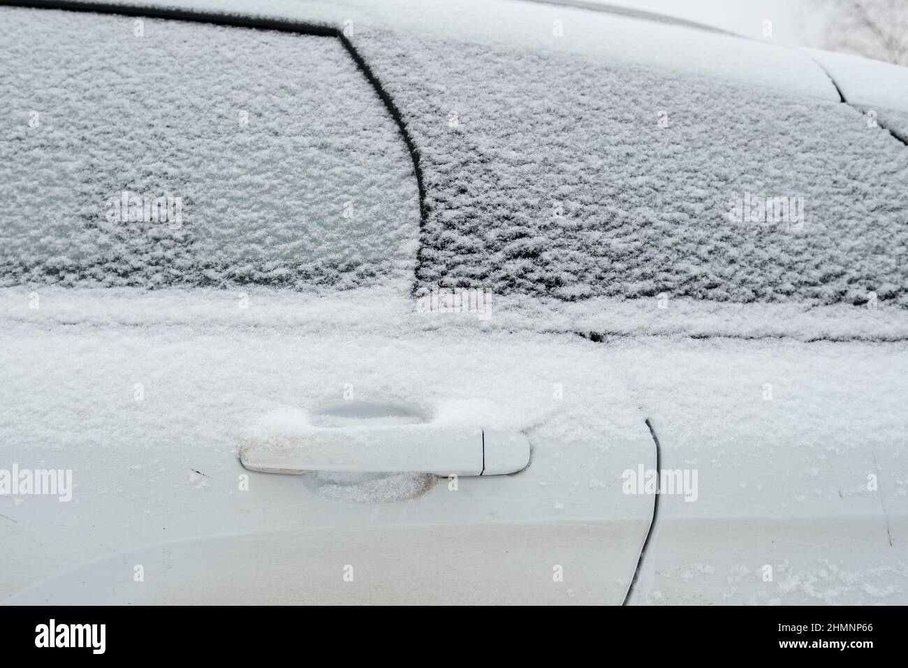 Snow-covered doors and windows of a car, outdoors, on a winter day ...