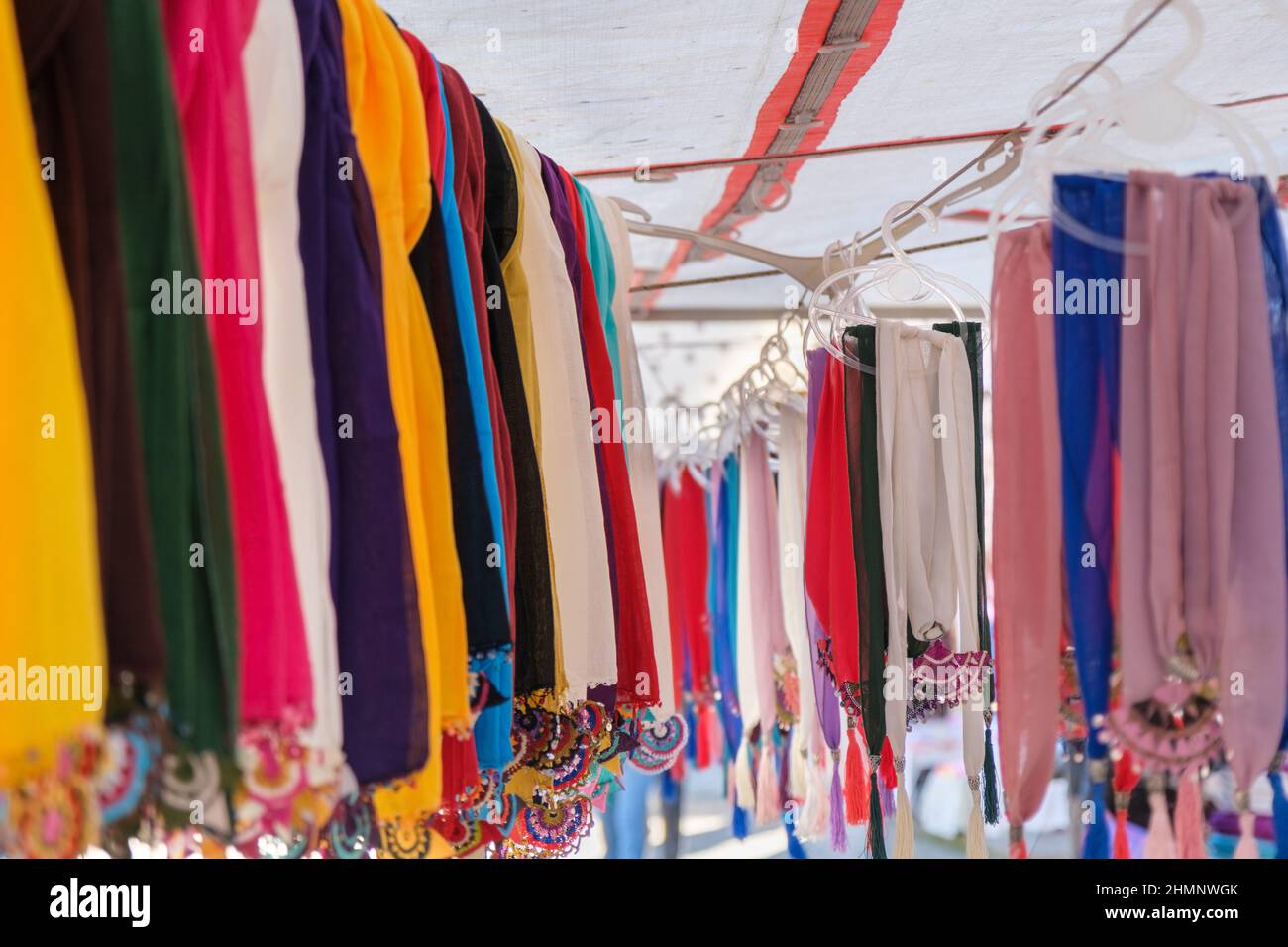 Colorful handmade scarves lined up on a rope hanger in woman producer ...