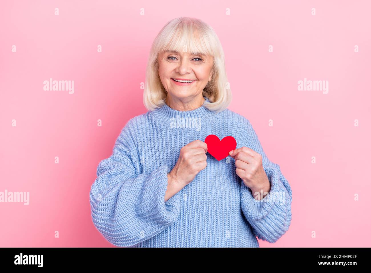 Portrait of attractive cheerful grey-haired woman holding heart card ...