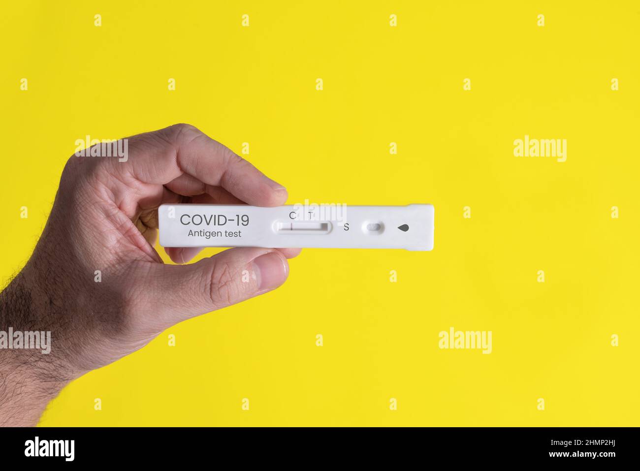 Male hand showing negative covid-19 and omicron antigen test on yellow ...