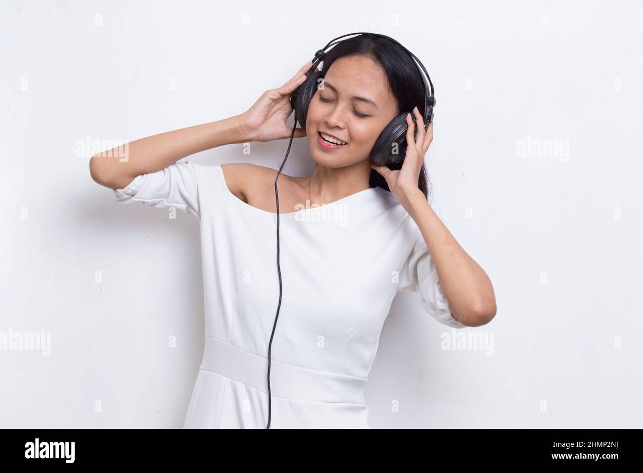 Beautiful young asian woman listening to music isolated on white ...