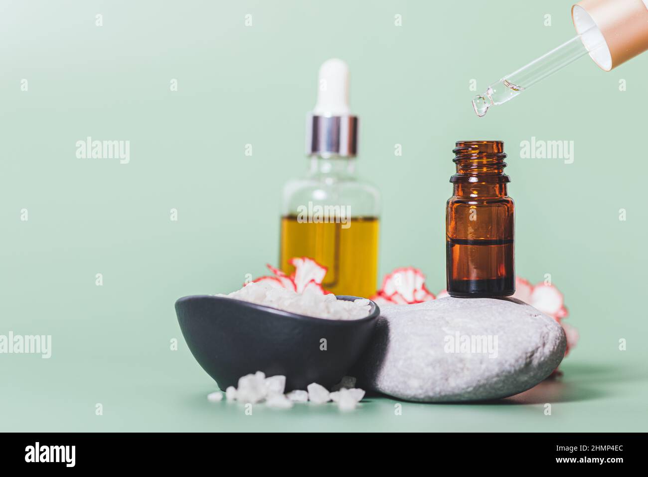 Essential oil dripping into bottle from pipette next to bath salt and ...