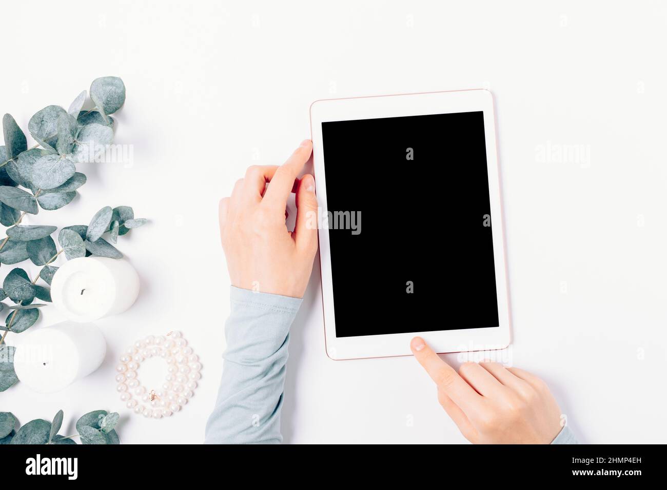 Female hands using tablet pc with blank display next to pearl necklace ...
