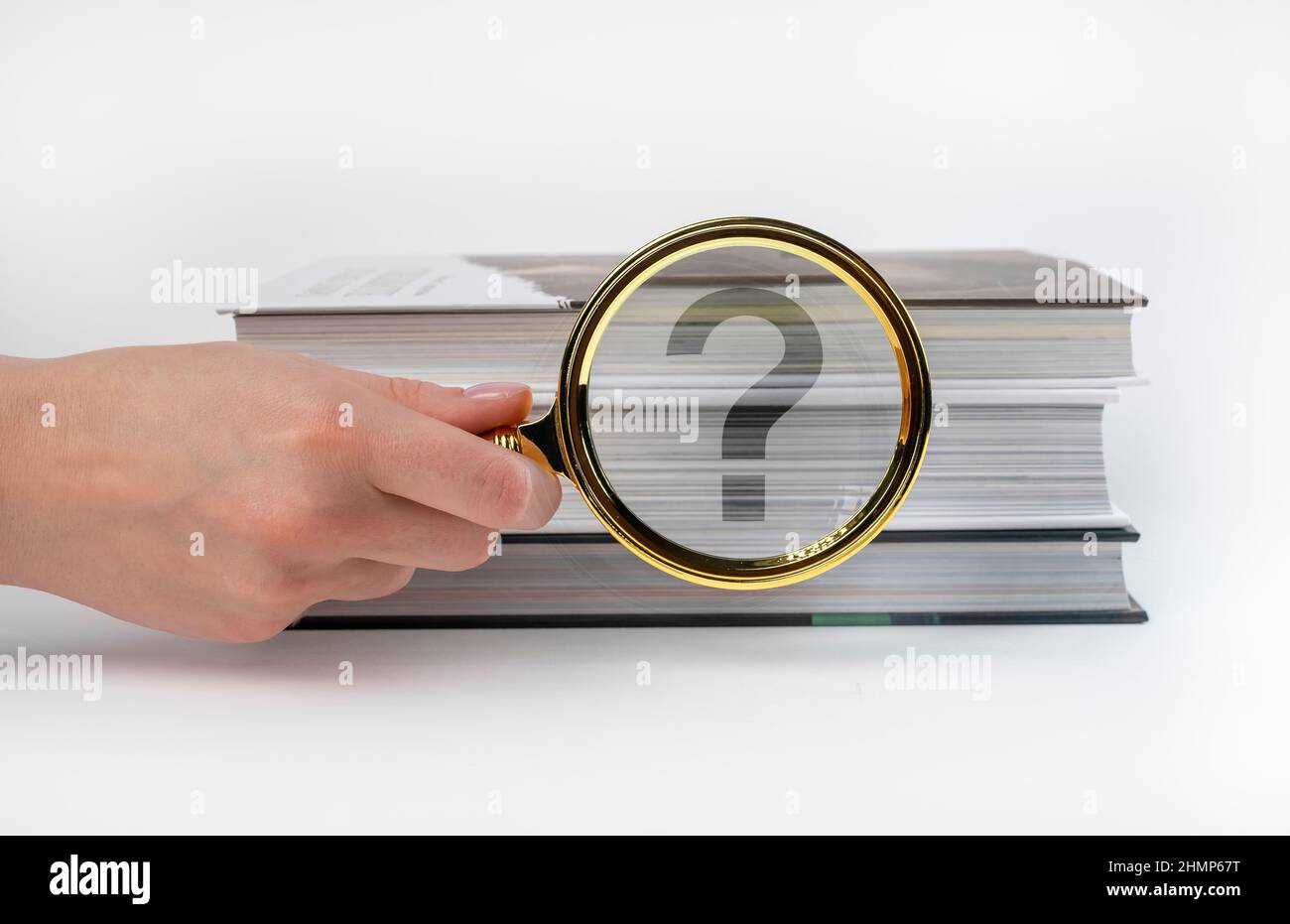 Questions and answers concept. Hand holding magnifying glass near books ...